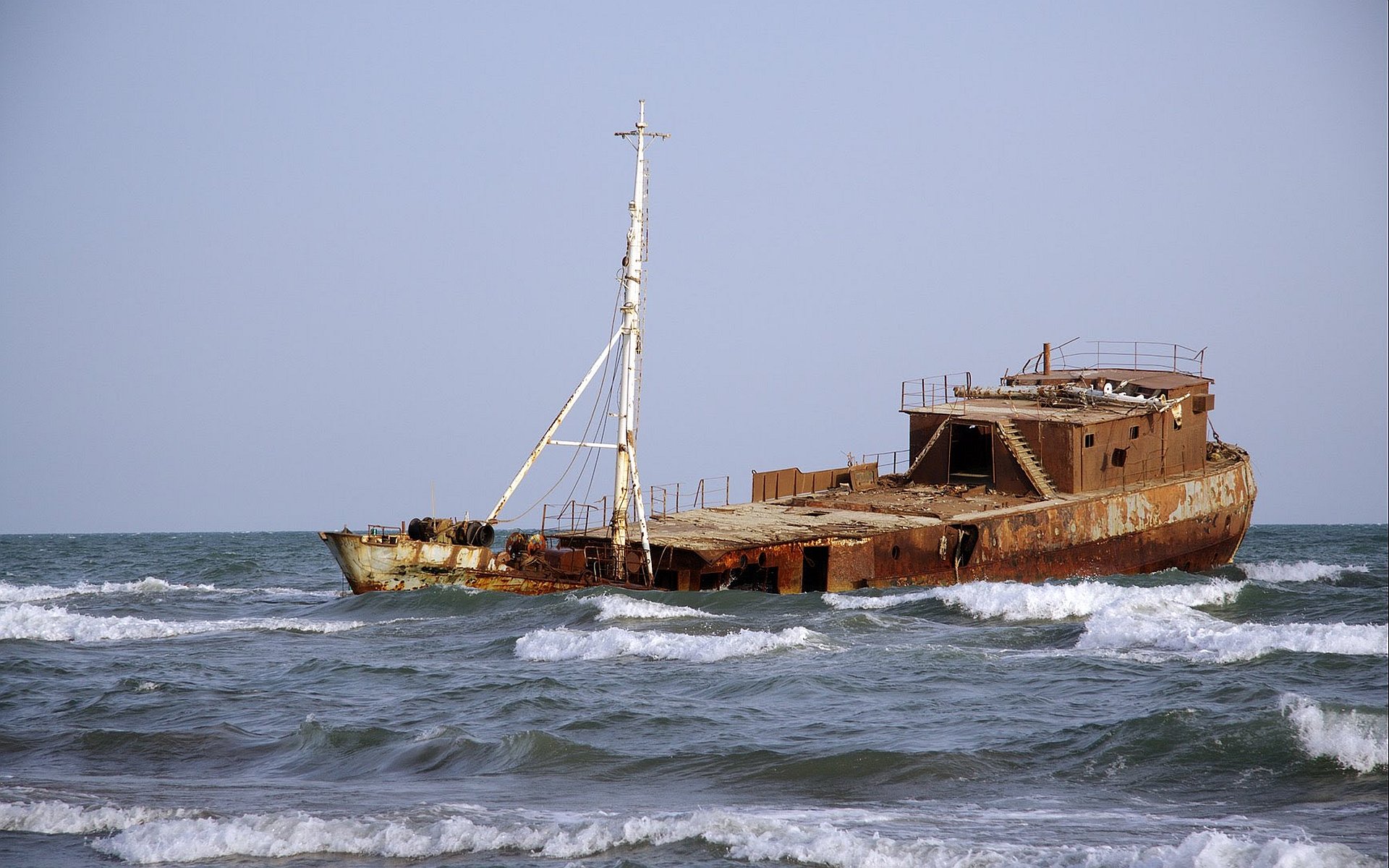 Rusting Relic: HD Wallpaper of a Weathered Shipwreck in Ocean Waves
